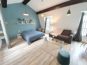 Uma sala de estar moderna com uma cama, um sofá, uma mesa de centro de vidro e uma parede azul.