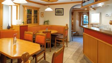 Um restaurante com interior de madeira, área de bar e espaço de refeições com cabines e mesas.