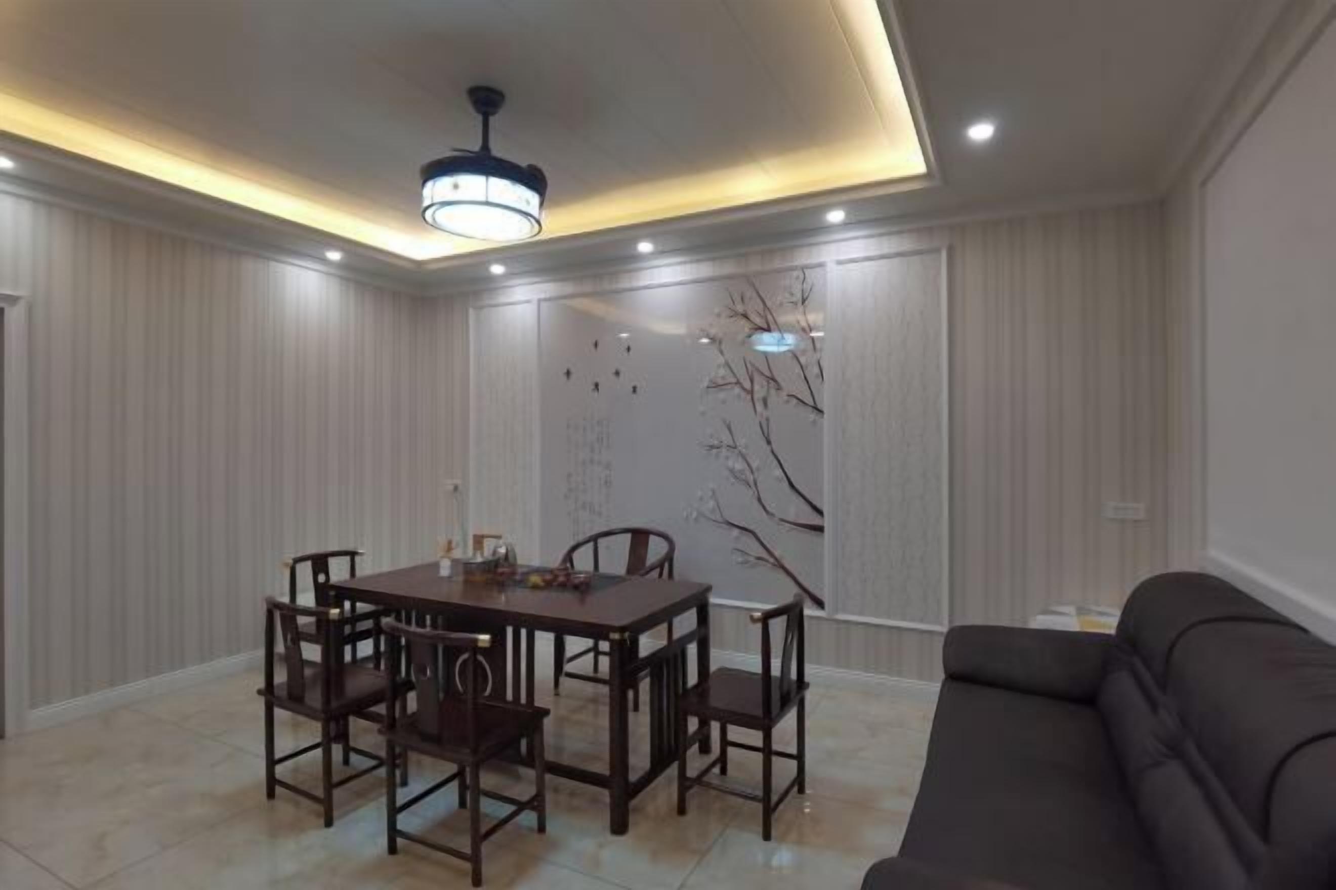Uma área de refeições com uma mesa e cadeiras de madeira escura, um lustre e uma parede com painéis verticais.