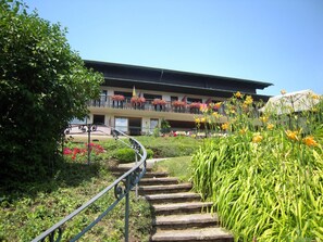 Um hotel com uma escadaria de pedra que leva a uma varanda com floreiras.