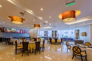 Um restaurante amplo com várias mesas e cadeiras, área de bar e iluminação pendente.