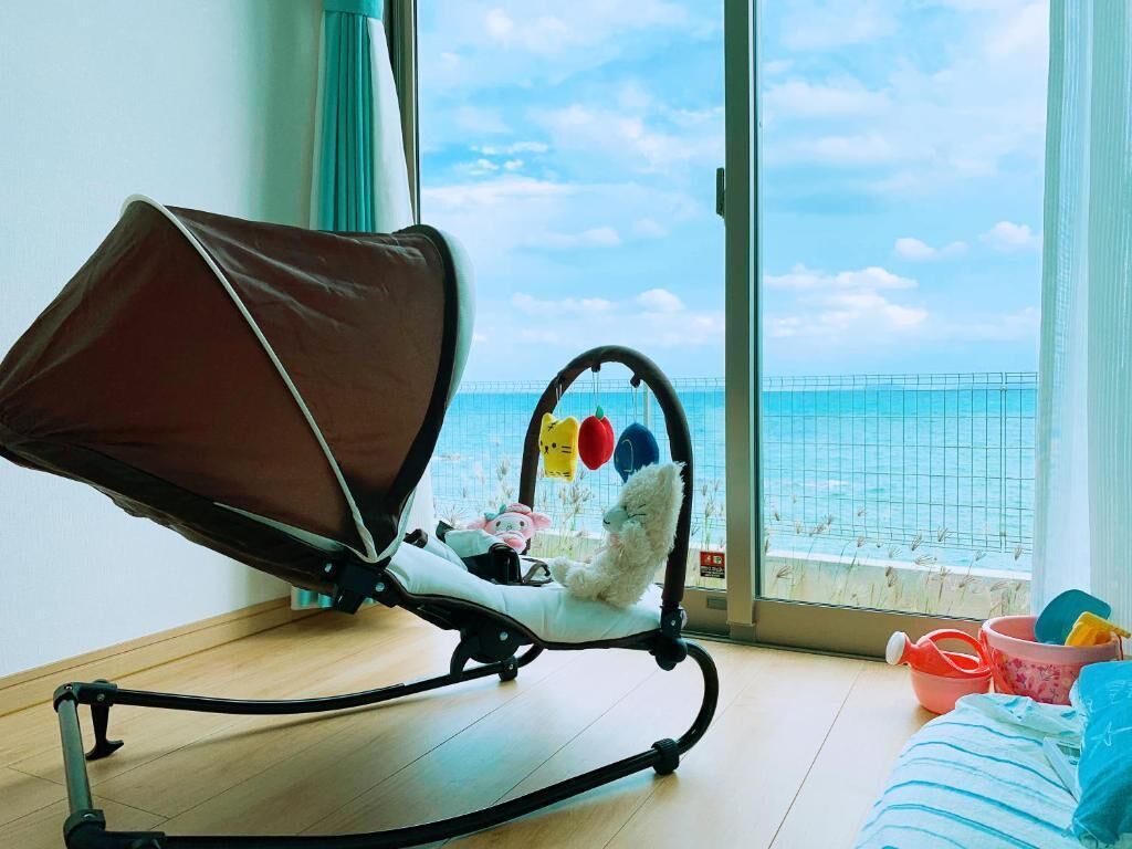 Quarto com vista para o mar, um balanço para bebê e janela com vista para a praia.
