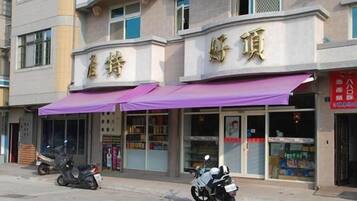 Edifício com fachada e toldo roxo. Scooters e uma motocicleta estacionados em frente.
