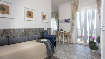 Quarto moderno com sofá, escrivaninha e vista para o exterior.