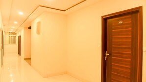 Um corredor com uma porta de madeira identificada com o número 306 e um chão de azulejos.