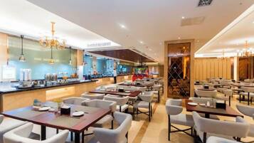 Restaurante moderno de hotel, com várias mesas e cadeiras, área de bar e vista para a paisagem urbana.
