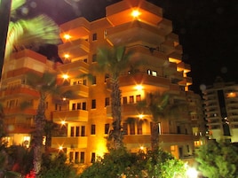Hotel com vários andares, varandas e iluminação externa aconchegante.