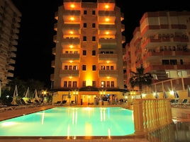 Hotel com piscina, várias varandas e área de bar.