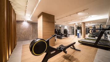 Uma academia moderna com equipamentos de cardio, máquinas de peso e um painel de espelhos.