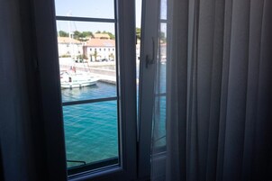 Vista da janela com vista para um porto de iates e edifícios ao longe.