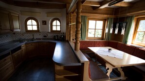 Uma cozinha com armários de madeira, uma ilha grande e um espaço de refeições com um banco.