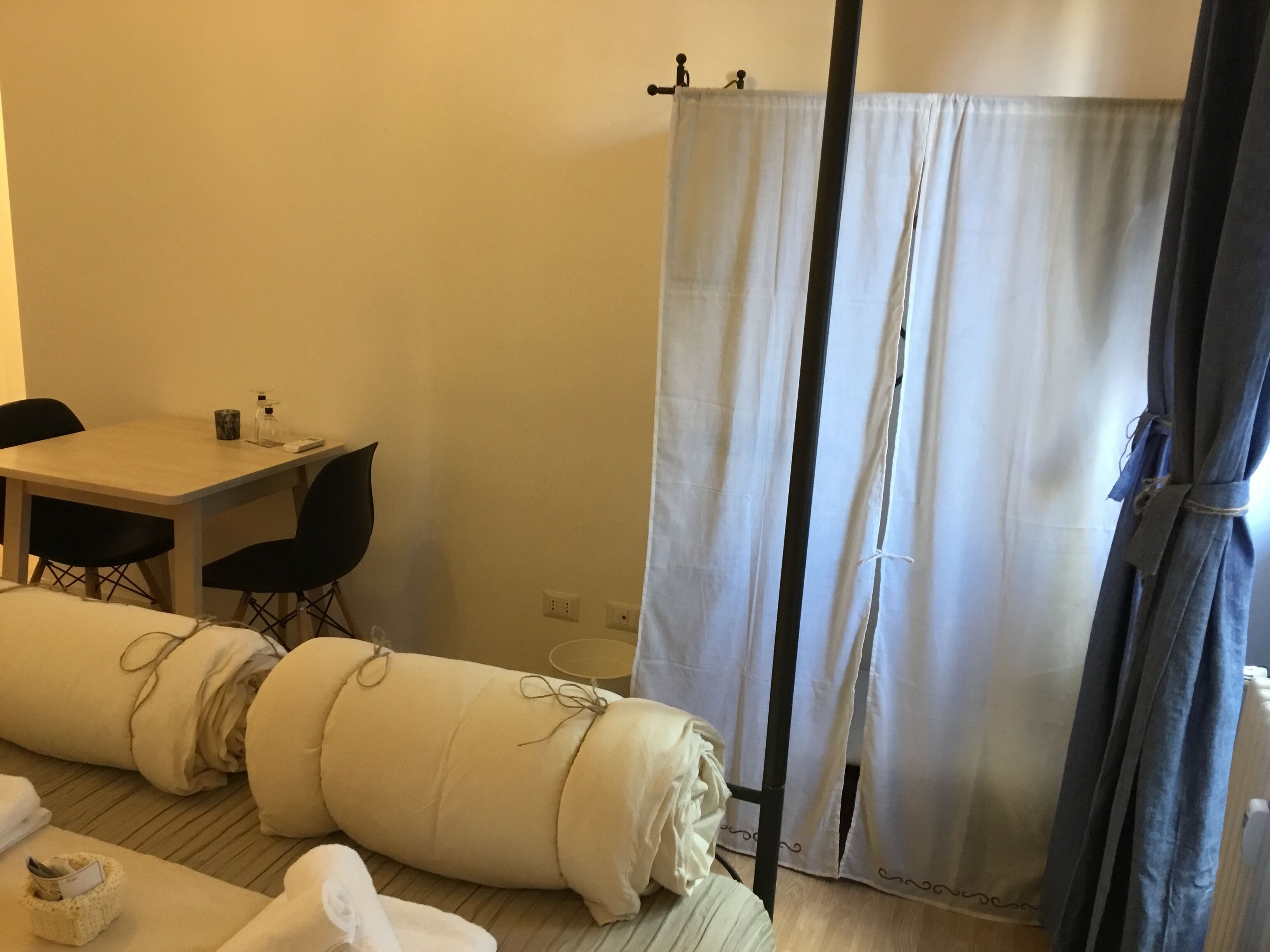 Um quarto com uma cama, uma mesa, duas cadeiras e um cortinado de chuveiro.