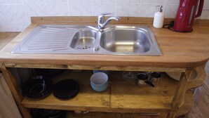 Cozinha com bancada de madeira, pia de aço inoxidável e unidade de armazenamento embutida abaixo.