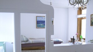 Quarto com cama, mesa de jantar com cadeiras, lustre e janela com vista.