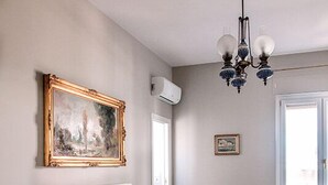 Quarto com cama grande, lustre, pintura e janela.