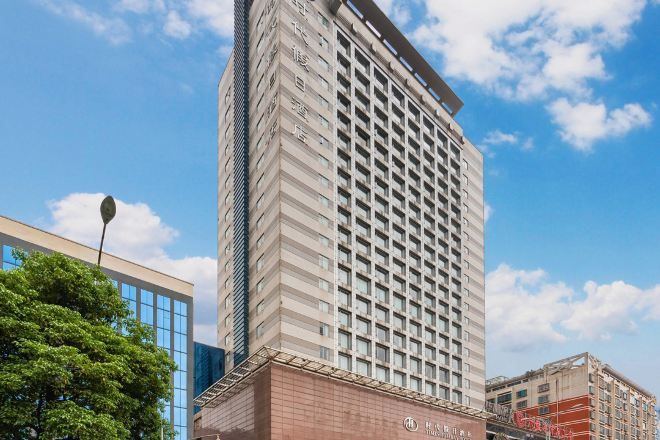 Um edifício de hotel alto com design arquitetônico moderno, destacando uma fachada de vidro e uma base de tijolos.