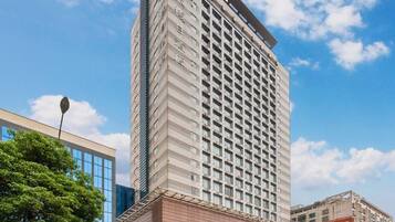 Um edifício de hotel alto com design arquitetônico moderno, destacando uma fachada de vidro e uma base de tijolos.