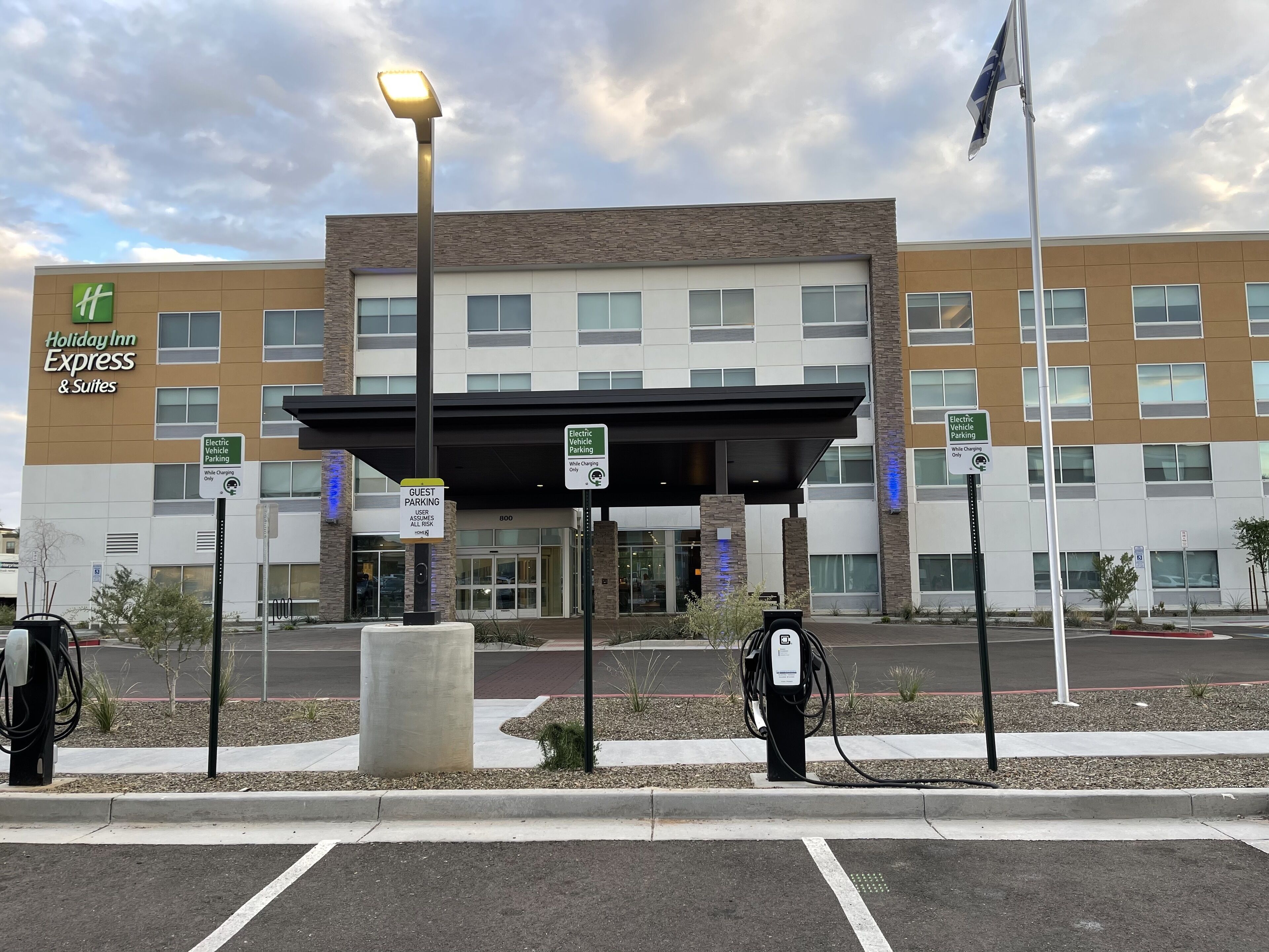 Edifício do Holiday Inn Express & Suites com estações de carregamento para veículos elétricos e estacionamento para hóspedes.