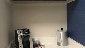 Uma cozinha compacta equipada com micro-ondas, cafeteira e lixeira.