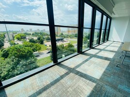 Quarto amplo com grandes janelas que oferecem vista para o horizonte urbano e áreas verdes.
