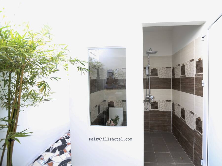 Casa de banho com chuveiro, paredes em azulejo e porta de vidro.