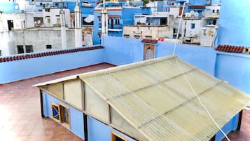 Um terraço no telhado com cobertura de metal corrugado, paredes azuis e piso de azulejos.