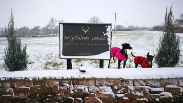 Placa de identificação do Hayeswood Lodge, uma pousada boutique, com parede de tijolos e chão coberto de neve.