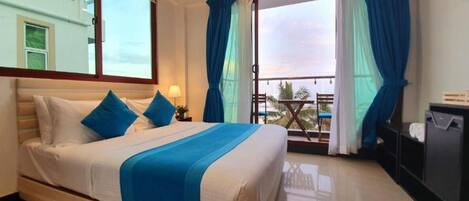Quarto de hotel com cama, mesa de cabeceira, penteadeira e varanda com vista.