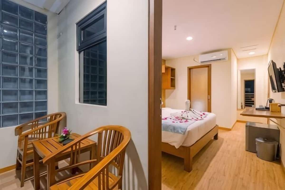 Quarto com cama, escrivaninha, cadeira e janela.