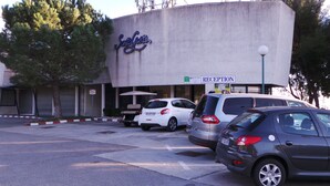 Um edifício com área de recepção e carros estacionados.