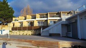 Um edifício com vários andares, varandas, uma escadaria e um espaço com deck de madeira.