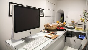 Uma mesa de escritório moderna com um computador, teclado, rato e diversos materiais de escritório.