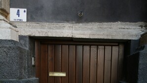 Uma porta de madeira com maçaneta e placa de latão, embutida numa parede de pedra, com a inscrição '4' acima.