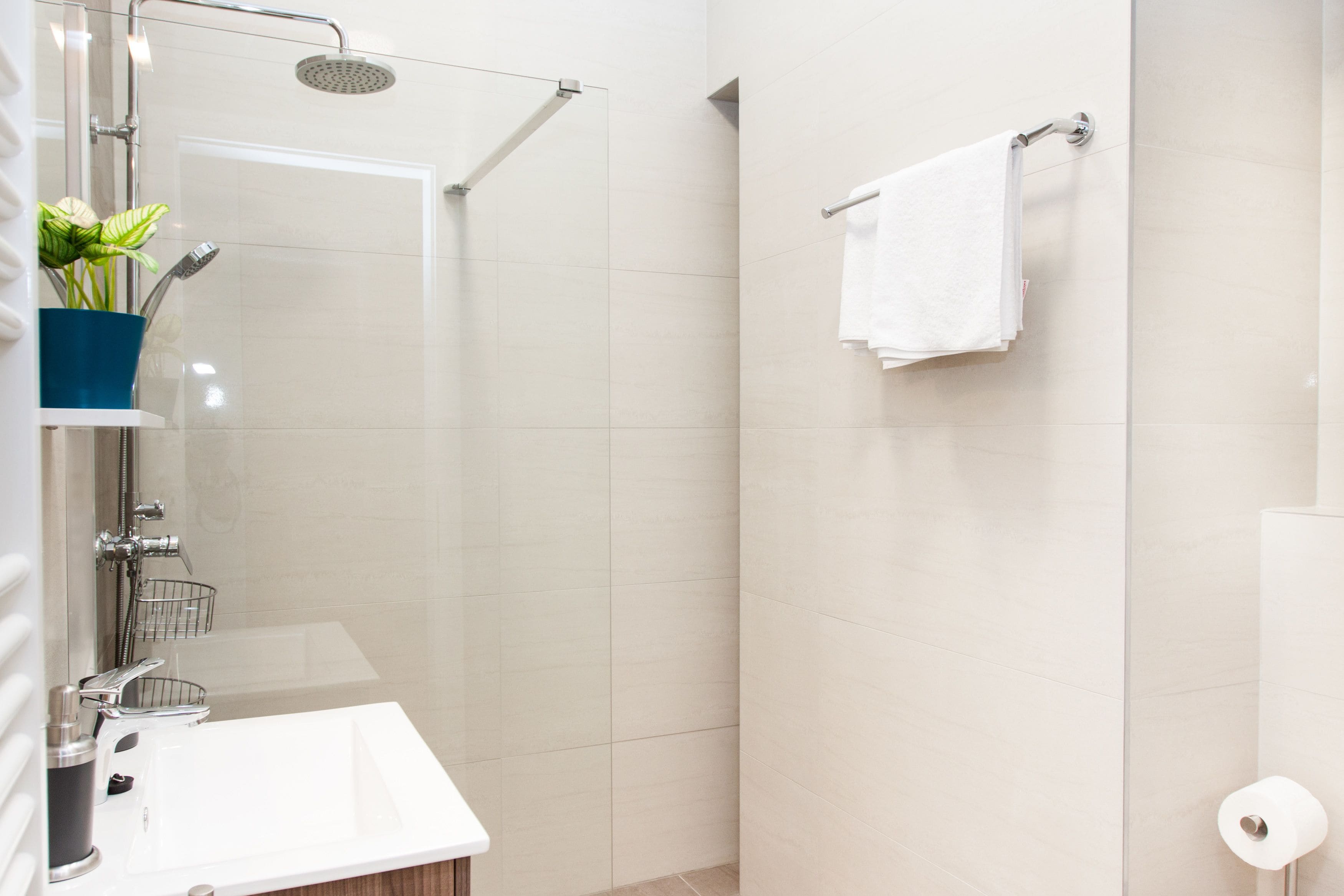 Uma casa de banho moderna com chuveiro, lavatório e suporte para toalhas.