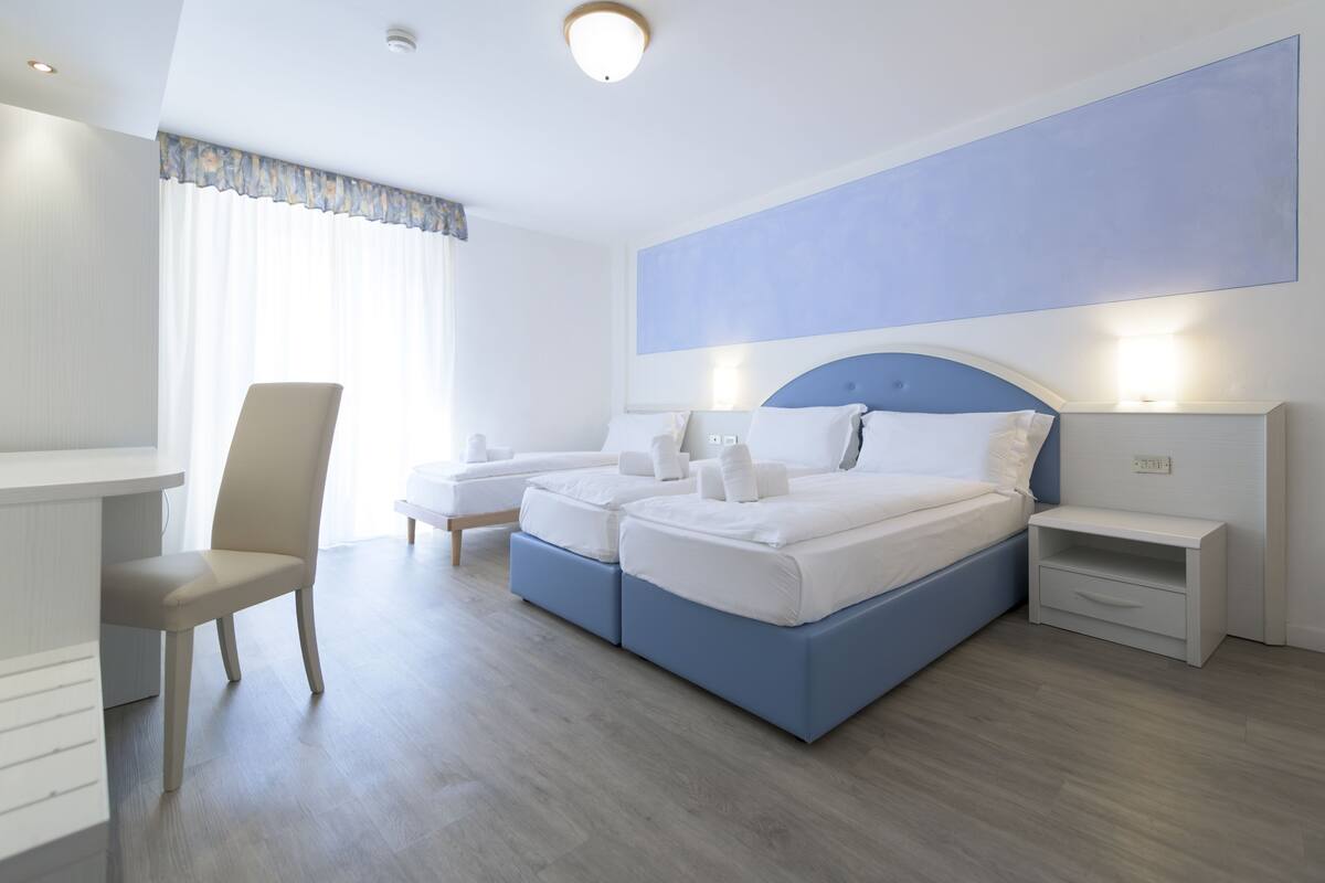 Quarto de hotel moderno com uma cama grande, uma escrivaninha e uma cadeira.