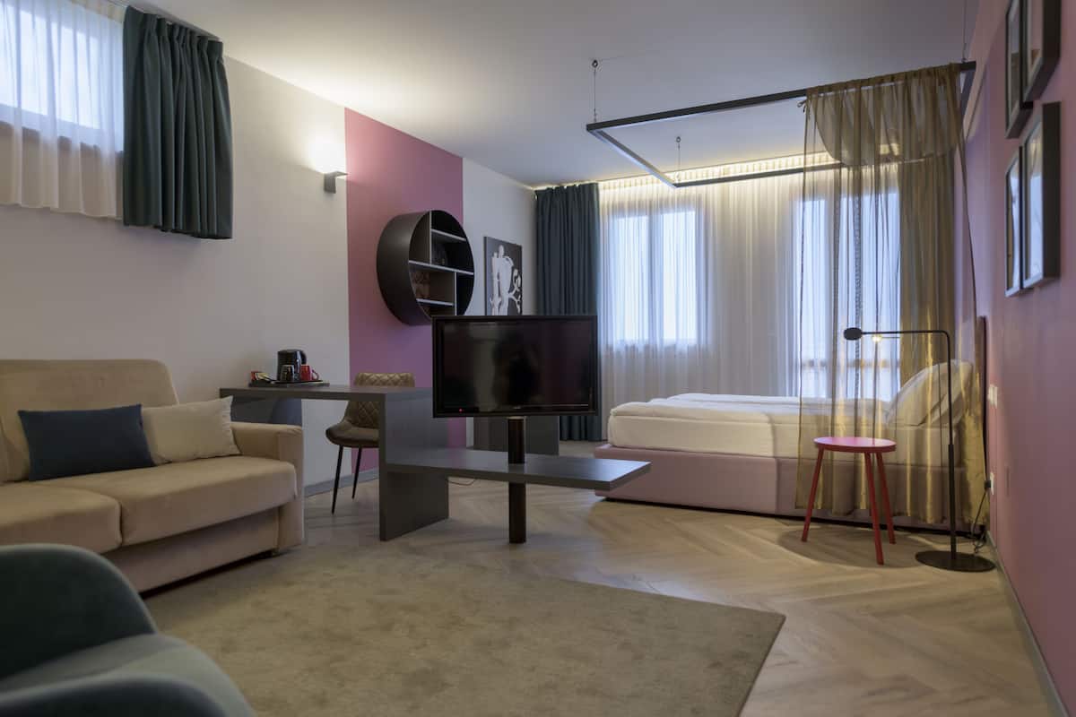 Uma sala moderna com um sofá, uma mesa de centro, uma TV, uma cama e uma pequena mesa.