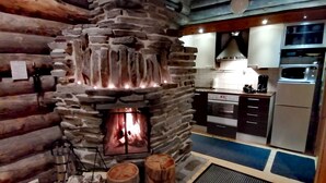 Cozinha rústica com lareira de pedra, lenha e eletrodomésticos modernos.