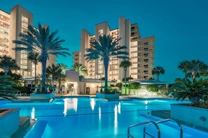 Um hotel com piscina, palmeiras e arquitetura moderna.