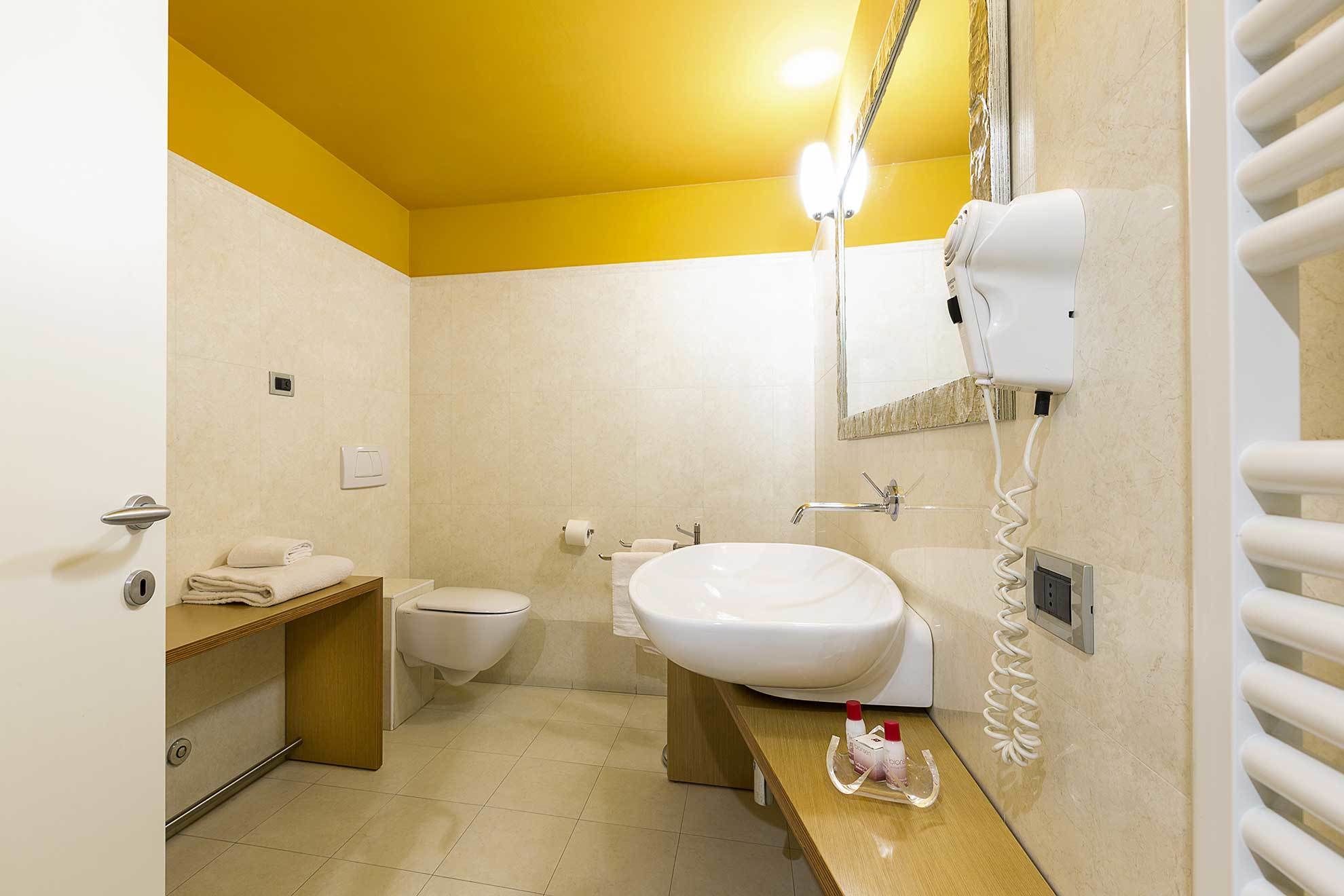 Casa de banho com sanita, lavatório e porta-toalhas.