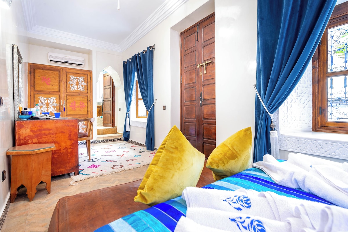 Quarto de hotel com cama, escrivaninha, cadeira e guarda-roupa.