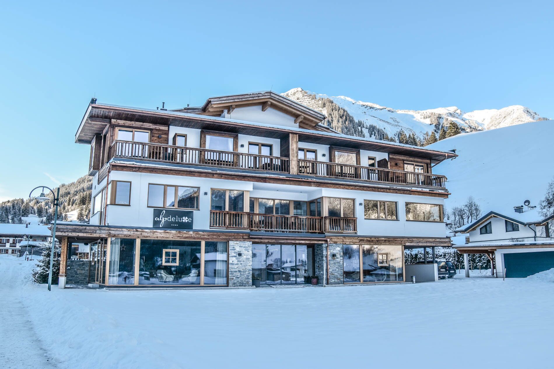 Um hotel com vários andares, varandas, janelas amplas e vista para montanhas cobertas de neve.