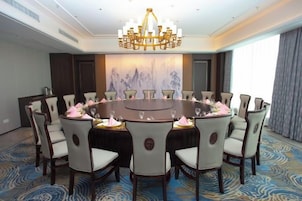 Sala de conferência com uma mesa redonda, cadeiras e um candelabro.