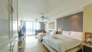 Quarto de hotel com uma cama grande, uma mesa, uma cadeira e uma varanda com vista.