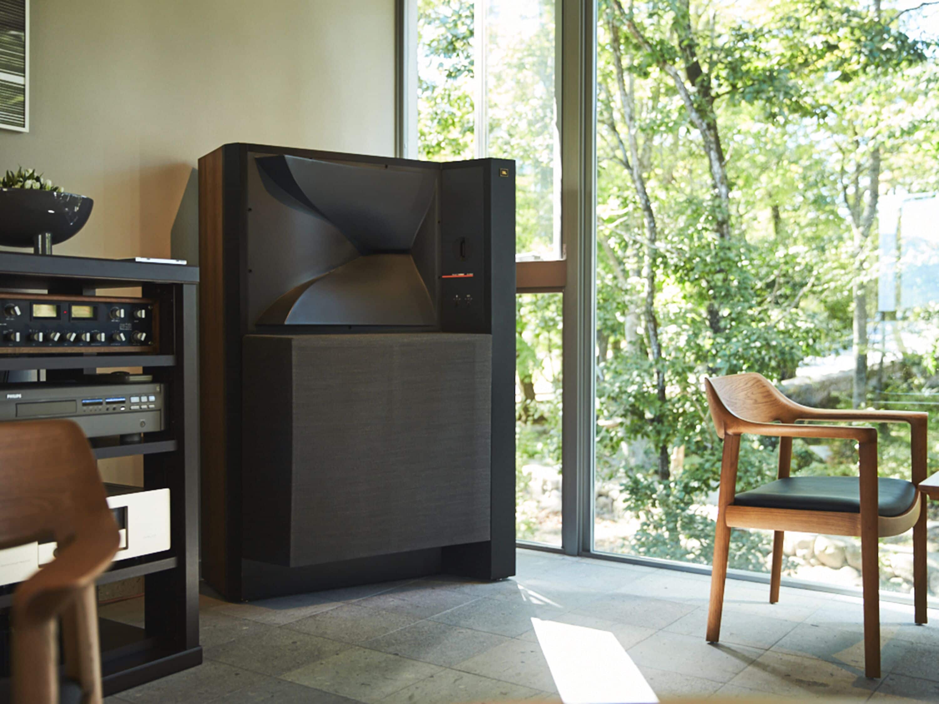 Cozinha moderna com forno embutido, máquina de café e uma grande janela com vista para árvores.
