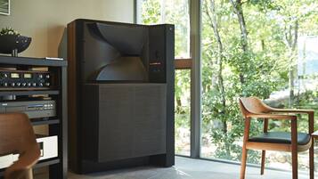 Cozinha moderna com forno embutido, máquina de café e uma grande janela com vista para árvores.