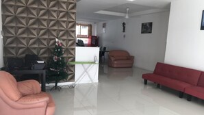 Uma sala de estar moderna com um sofá rosa, um sofá vermelho, uma árvore de Natal pequena e um balcão de recepção.
