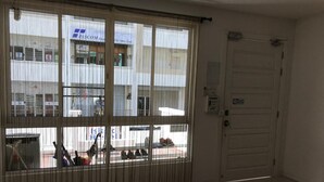 Quarto de hotel com janelas amplas, uma porta e chão ladrilhado.