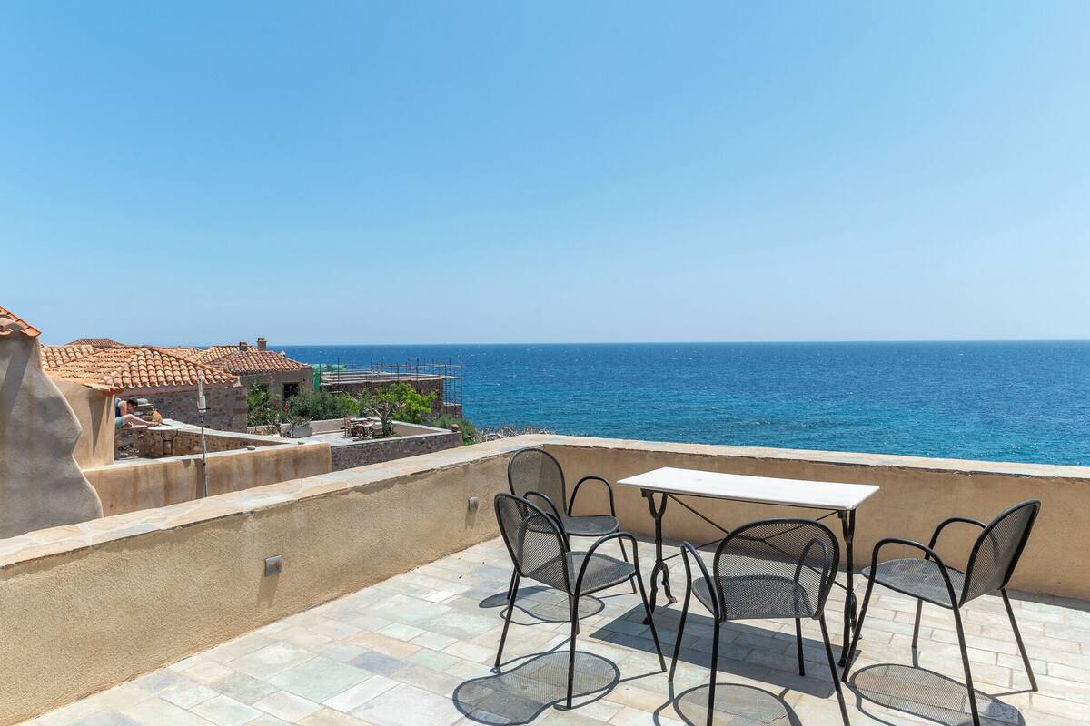 Terraço com mesa e cadeiras com vista para o mar.