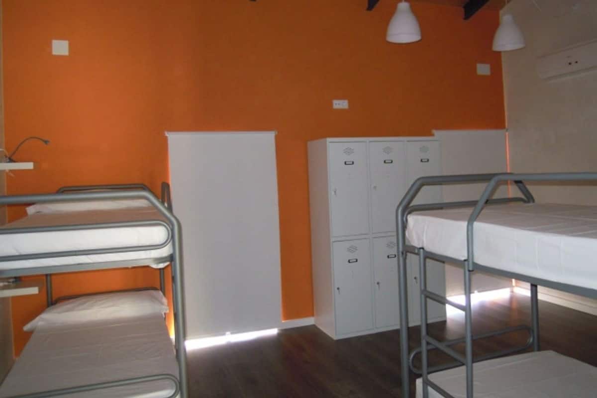 Um quarto de dormitório com beliches, um guarda-roupa e uma porta branca.