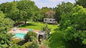 Um quintal com piscina, espreguiçadeiras e uma casa pequena.